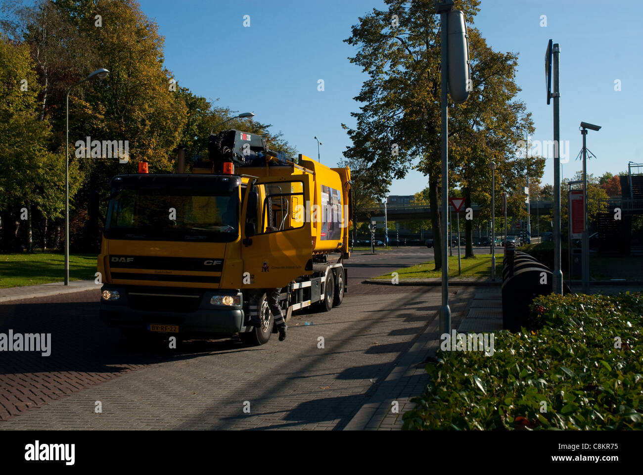 A council worker getting into a yellow recycling lorry having collected ...