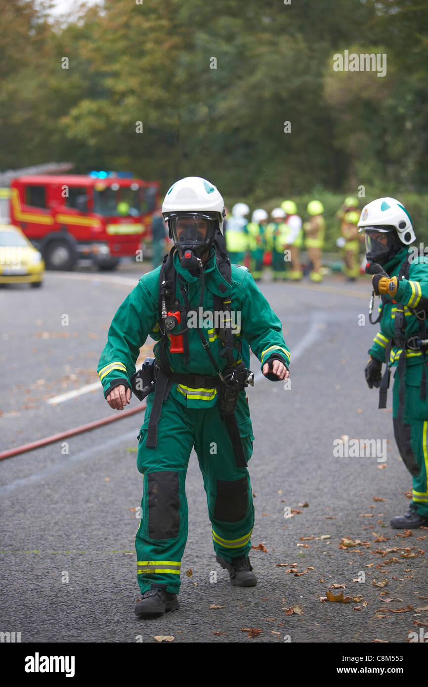 Paramedics wearing oxygen masks and fire crew attend a road traffic ...