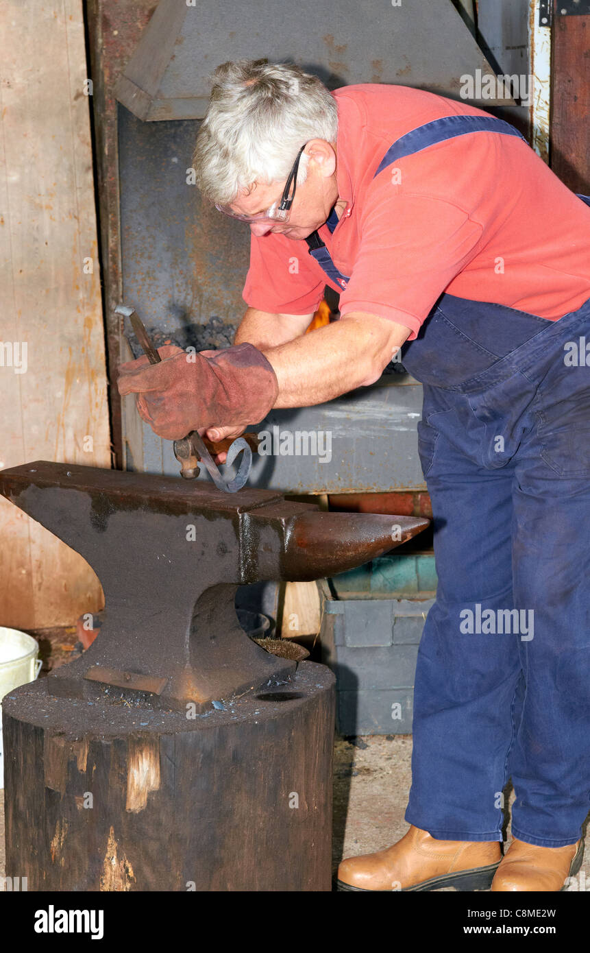 Blacksmith at work using a typical portable steel forge and traditional ...