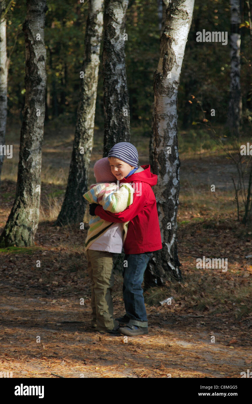 Two children embrace each other in autumn forest Stock Photo - Alamy