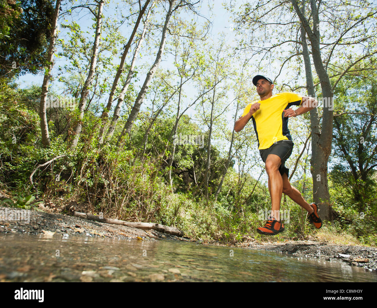 Mixed race man running through stream Stock Photo - Alamy