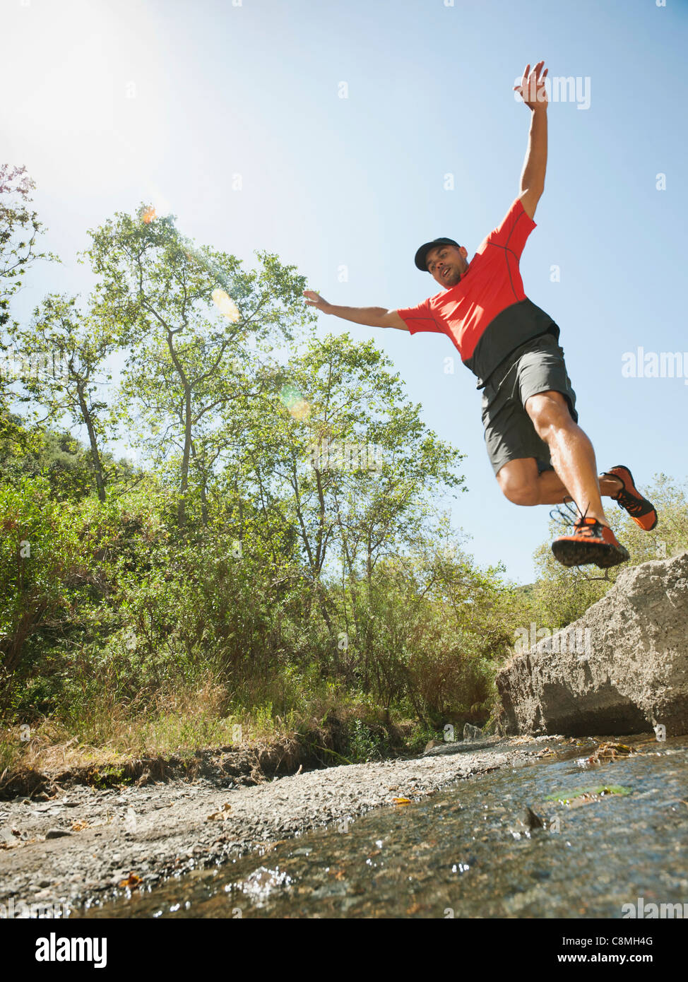 Mixed race man jumping into stream Stock Photo - Alamy