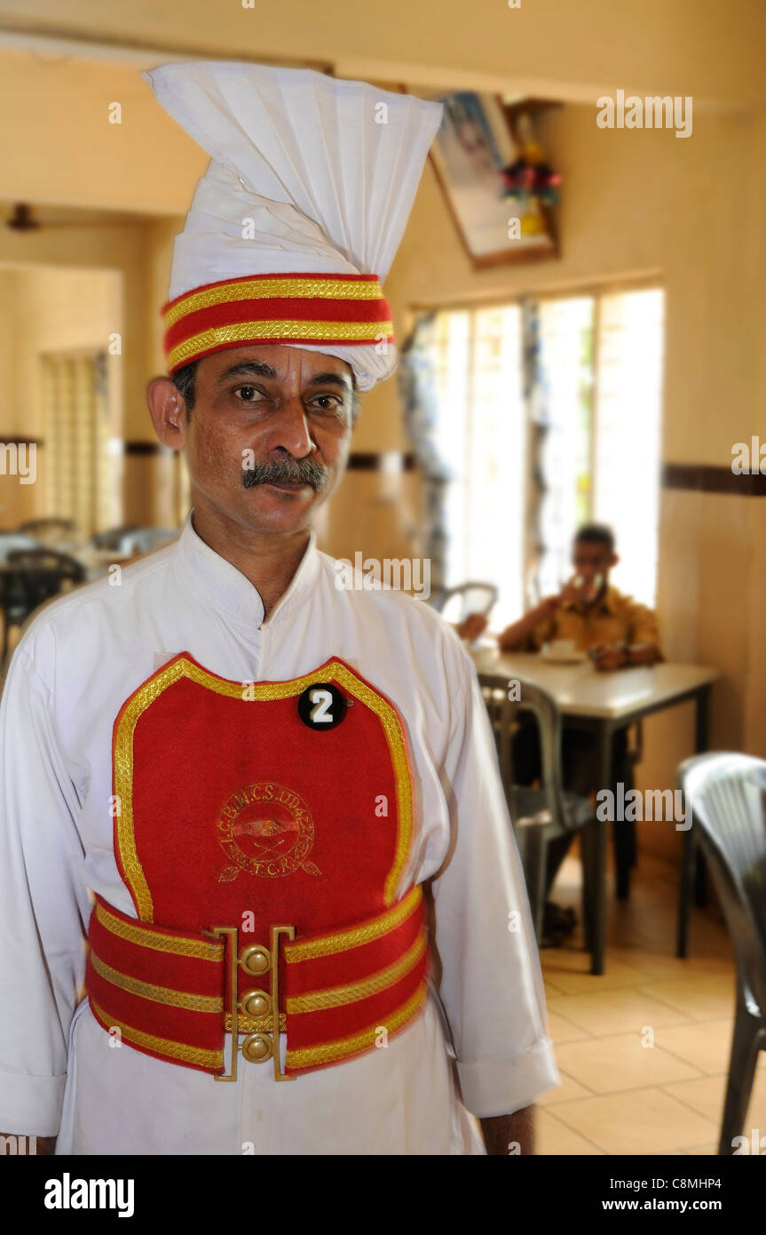 Tea waiter wearing the distinctive uniform of starched uniform and head ...