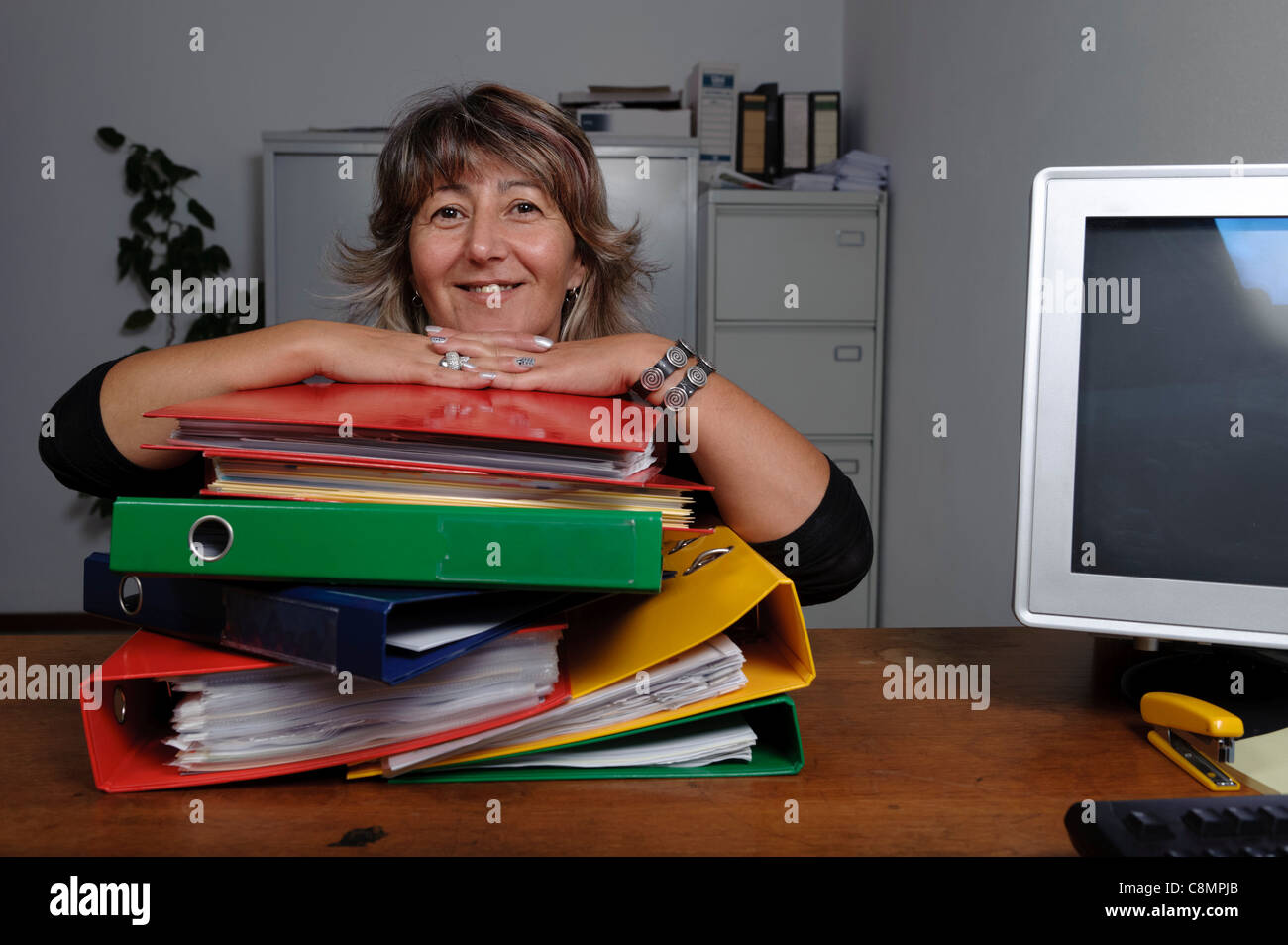 Female office worker on desk with stack of file folders on ring binders ...
