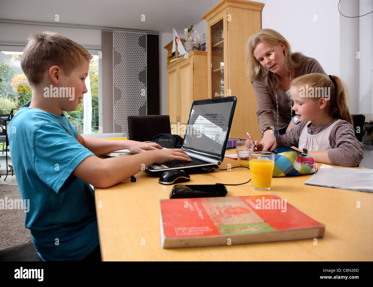 Brother and sister learning at home for school, getting assistance from ...