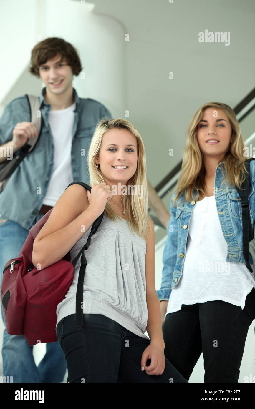 Three smiling students walking down interior stairs Stock Photo - Alamy