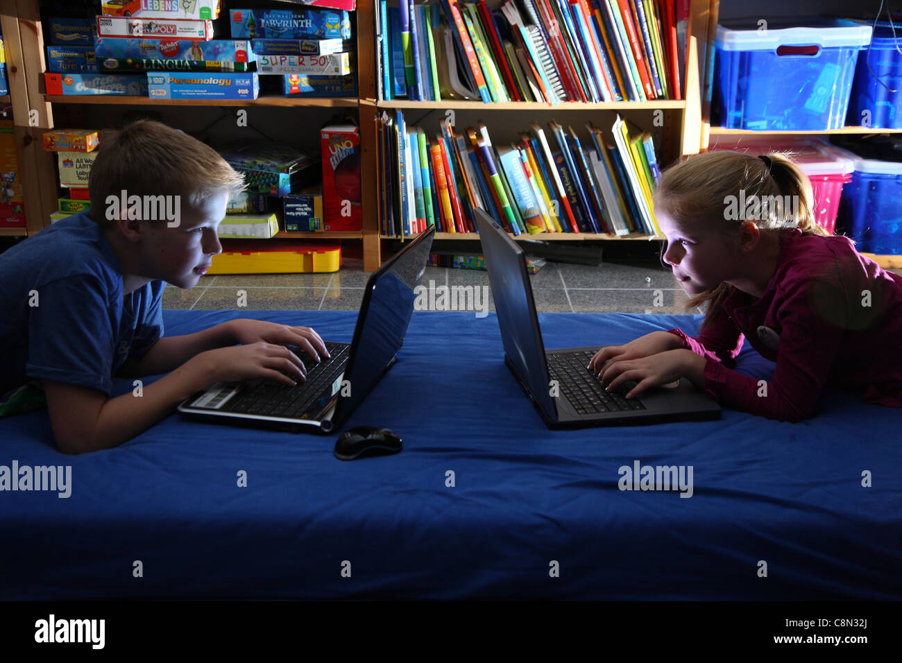 2 kids, girl 10, boy 13 years old, playing computer games on laptop ...