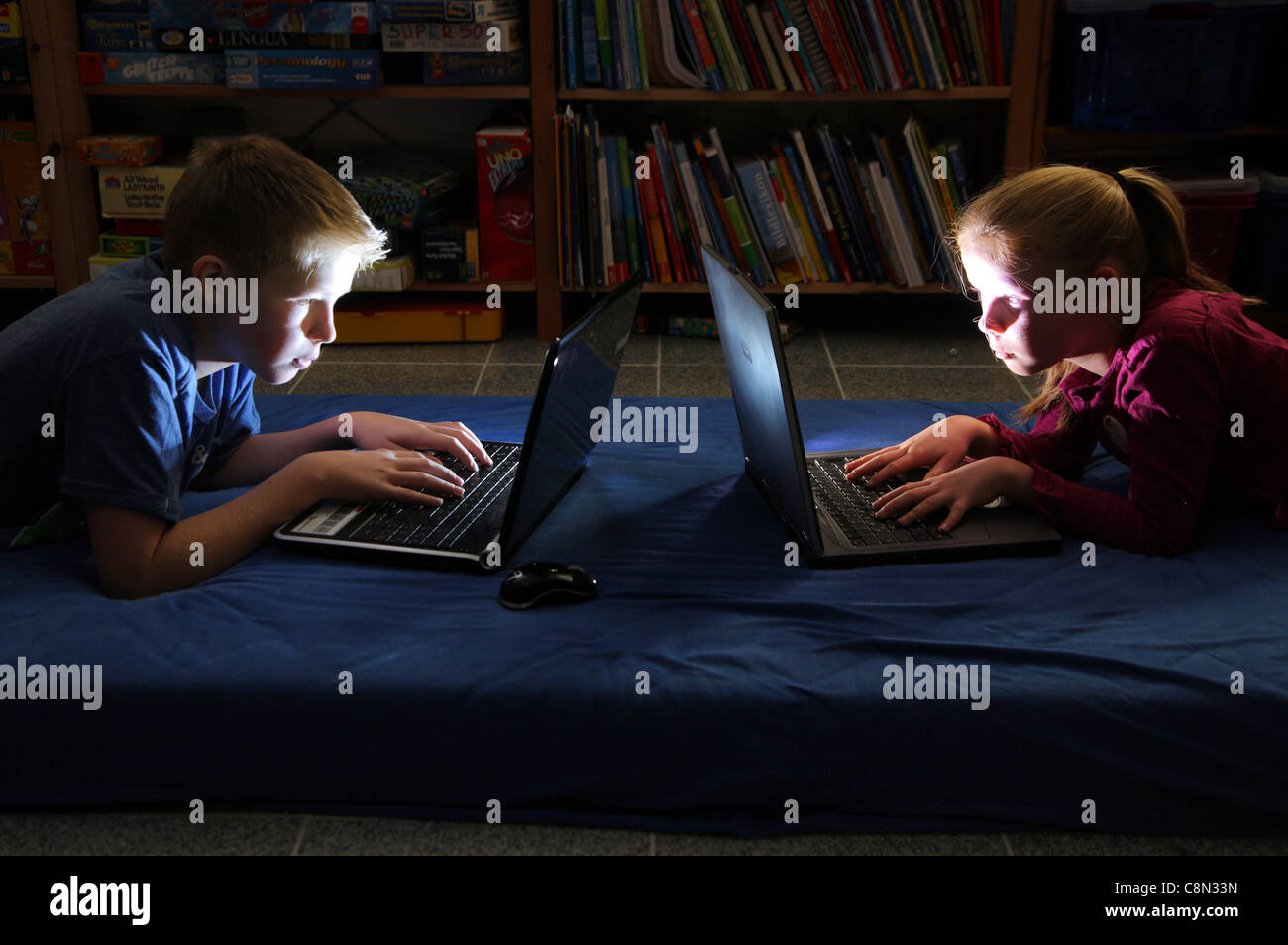 2 kids, girl 10, boy 13 years old, playing computer games on laptop ...