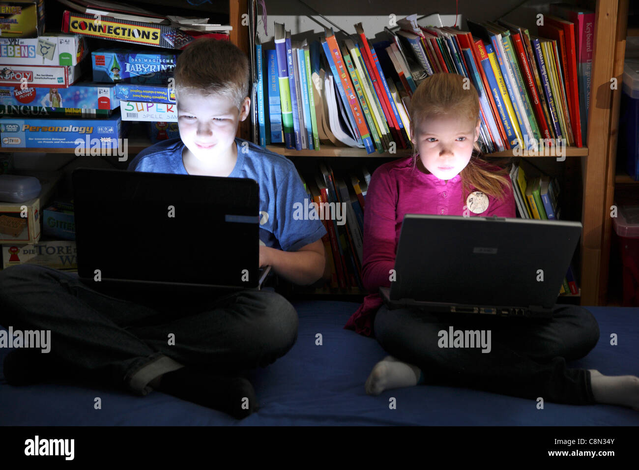 2 kids, girl 10, boy 13 years old, playing computer games on laptop ...