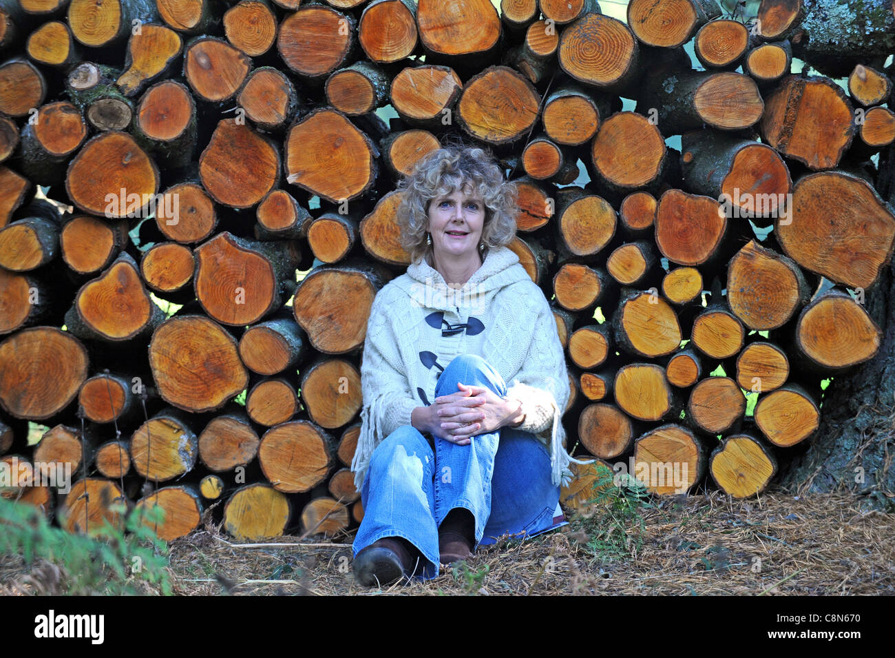 Middle aged woman wearing jeans and cream woolen poncho leans against ...