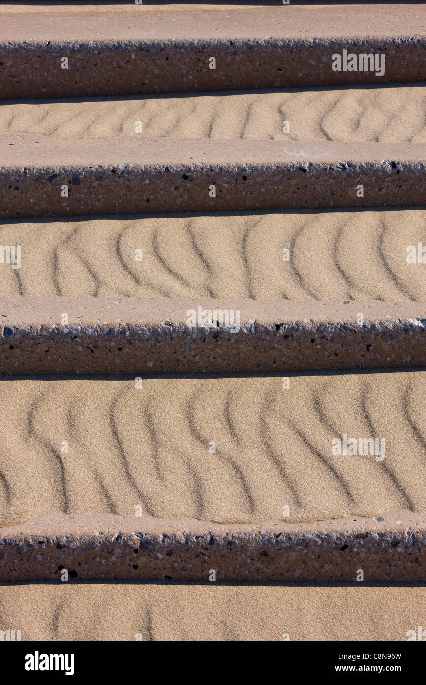 Patterns in the sand drifting on the concrete steps leading down to the ...