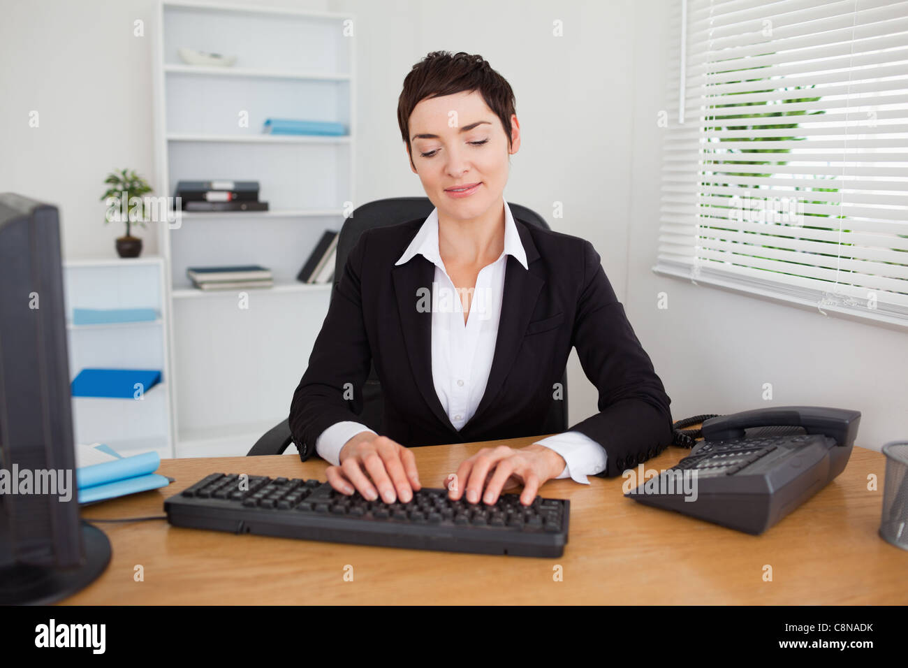 Serious secretary typing on her keybord Stock Photo - Alamy