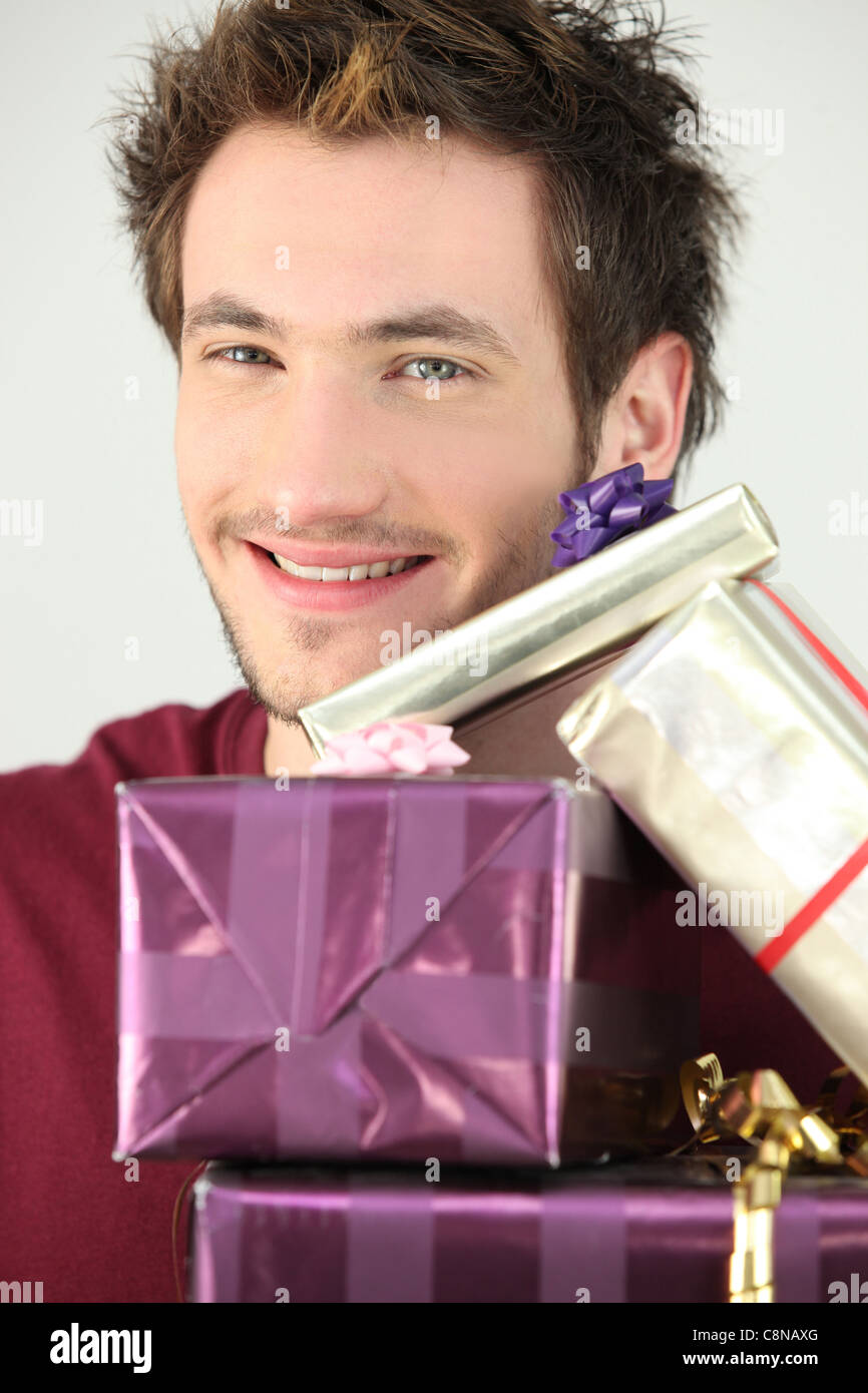 Young man with a pile of gifts Stock Photo - Alamy
