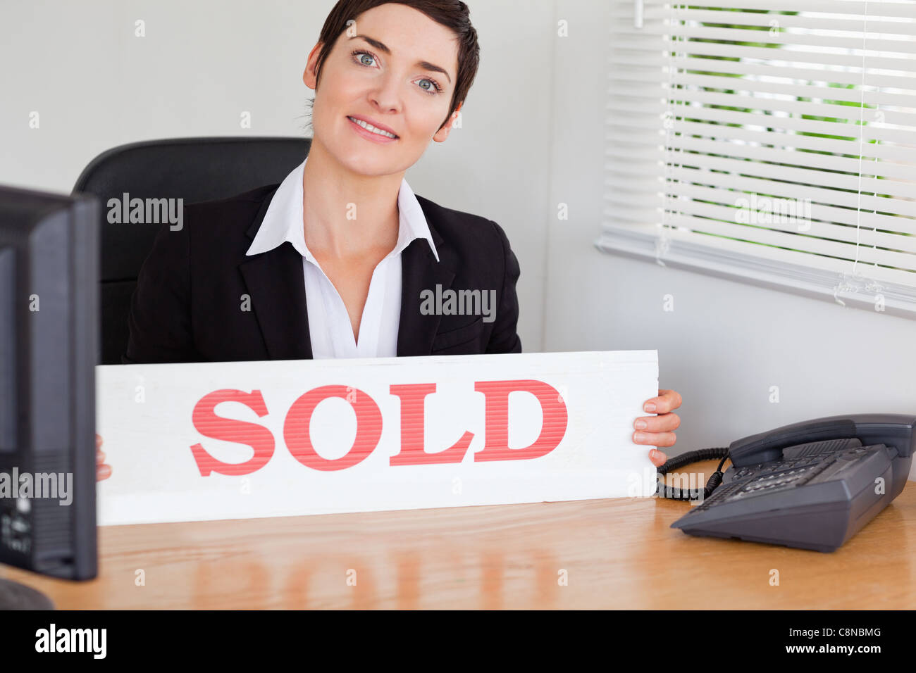 Smiling real estate agent with a sold panel Stock Photo - Alamy