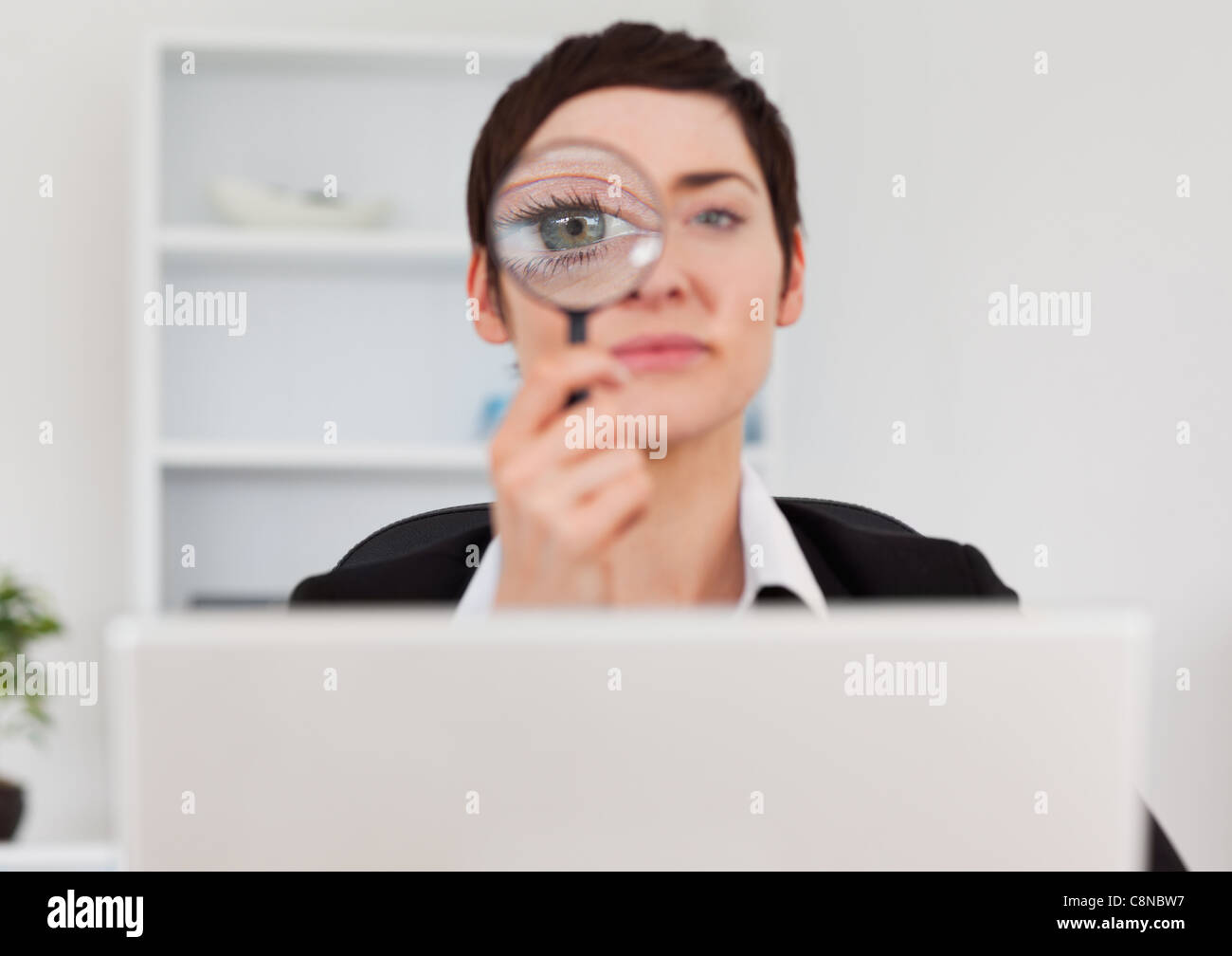 Office worker looking through a magnifying glass Stock Photo - Alamy