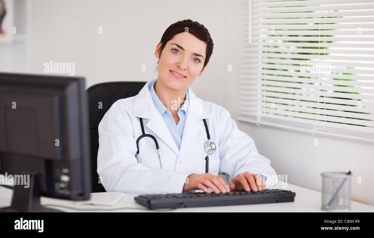 Smiling doctor typing with her computer Stock Photo - Alamy