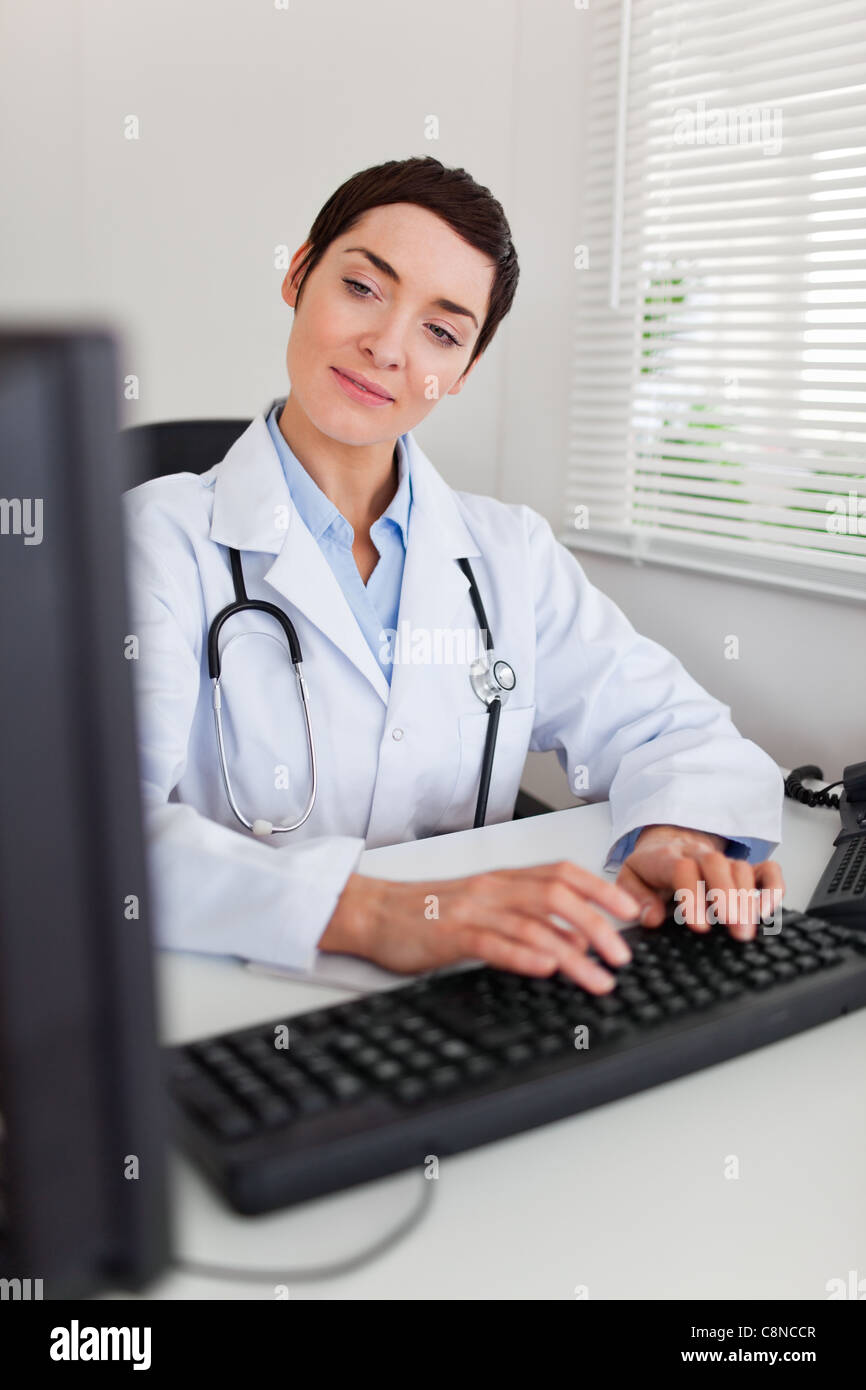 Portrait of a charming female doctor typing with her computer Stock ...