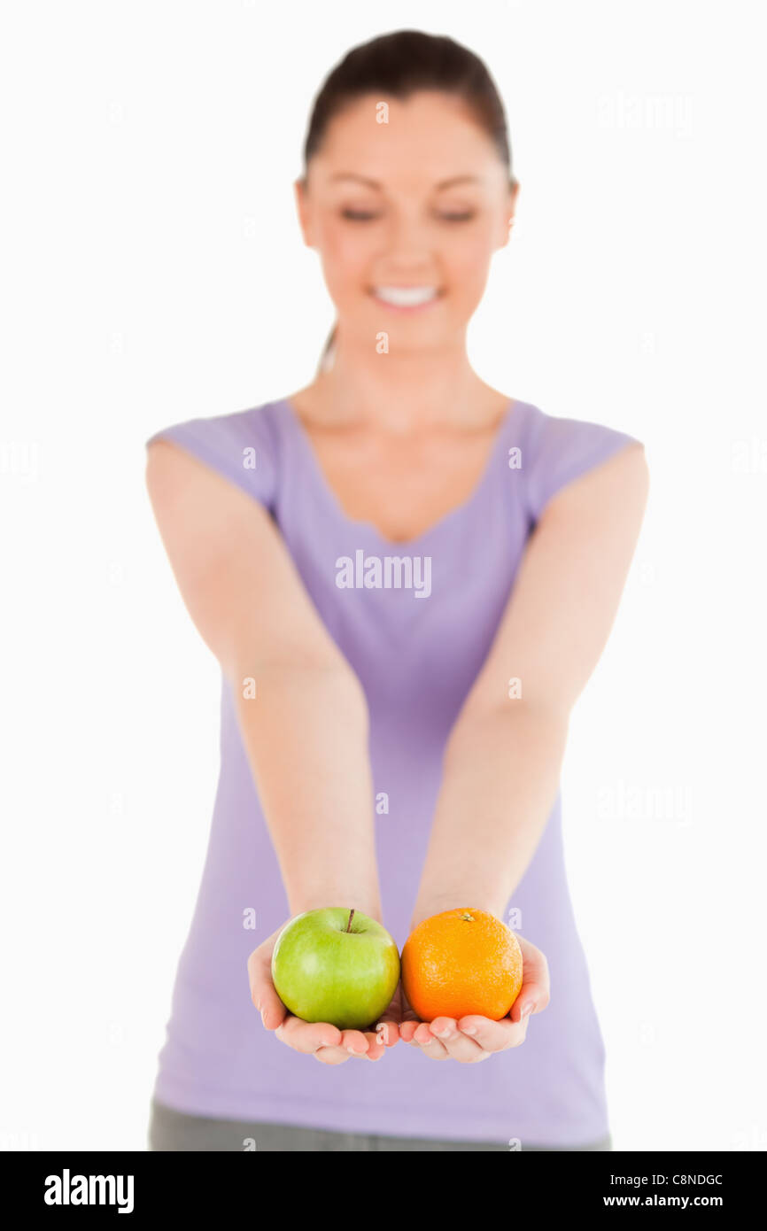 Attractive woman holding fruits while standing Stock Photo - Alamy