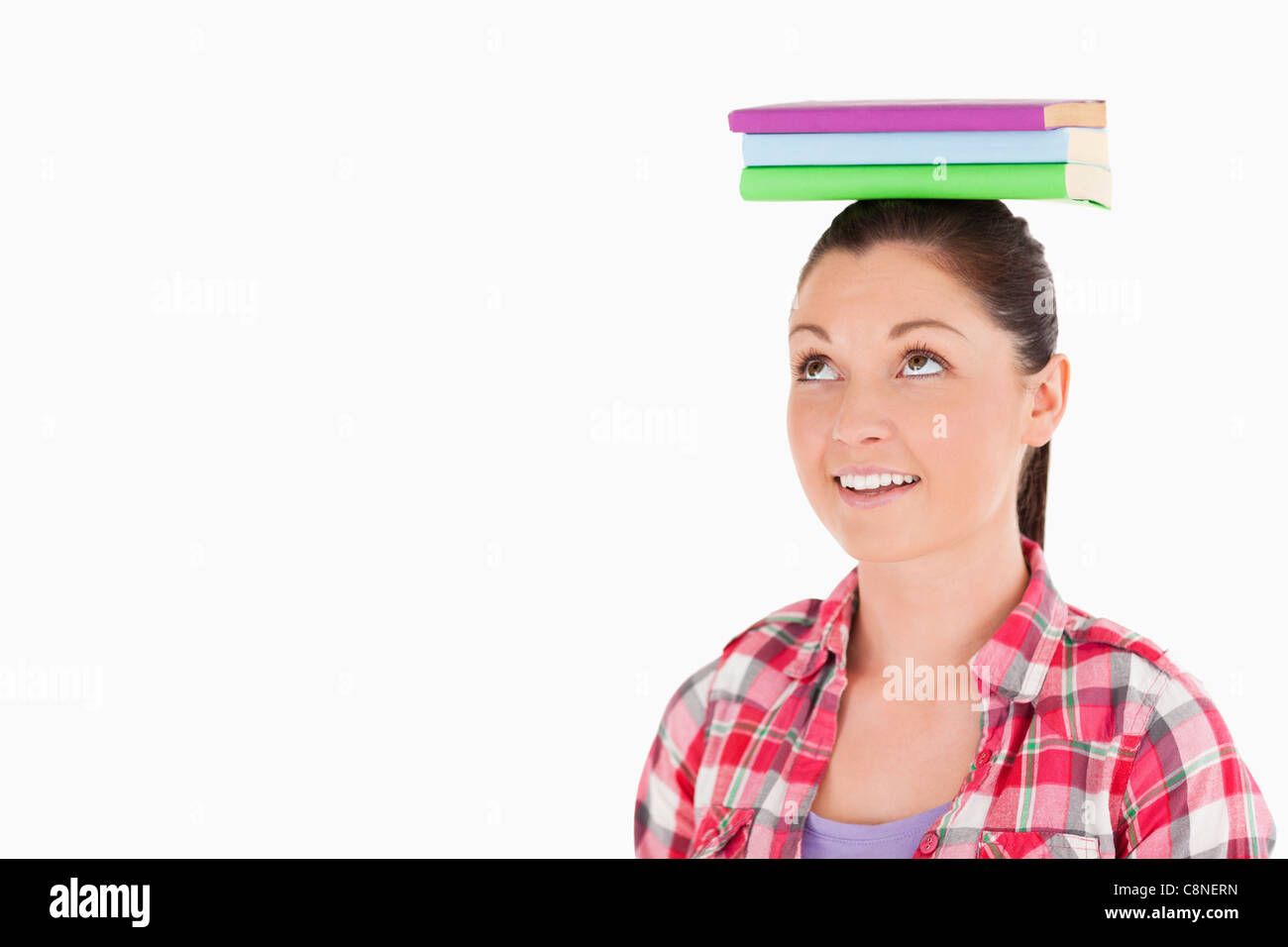 Attractive female holding books on her head while standing Stock Photo ...