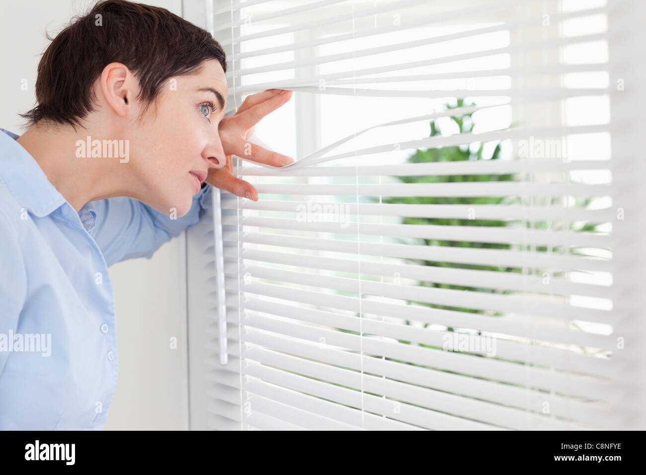 Woman peeking out a window Stock Photo - Alamy