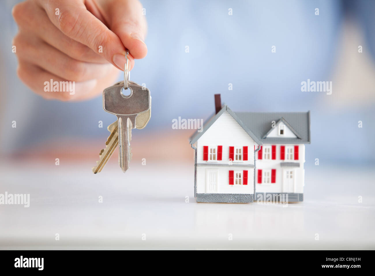 Woman holding keys next to a model house Stock Photo - Alamy