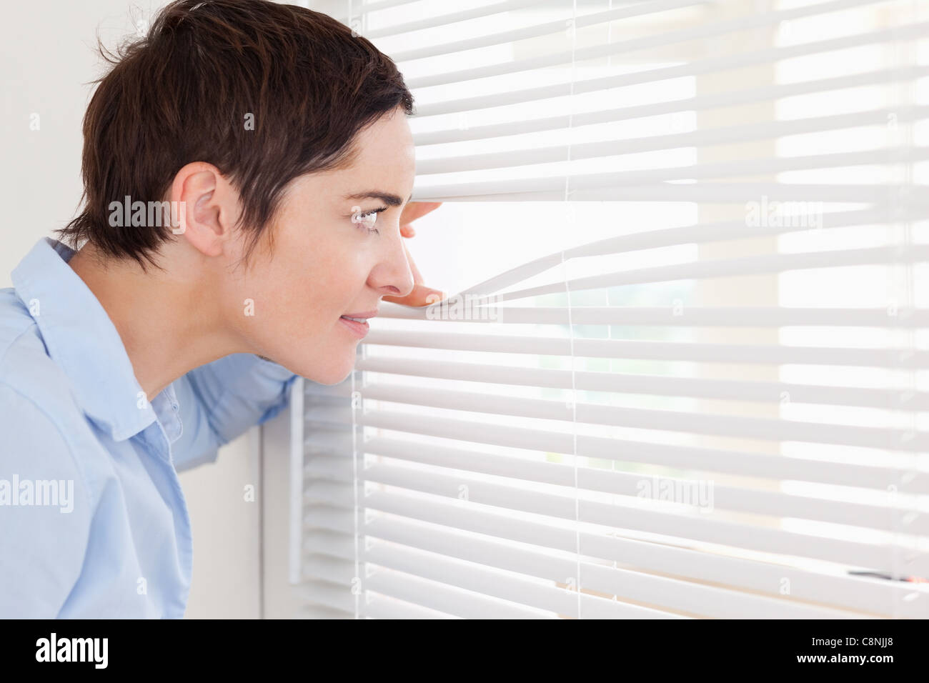 Beautiful woman peeking out a window Stock Photo - Alamy