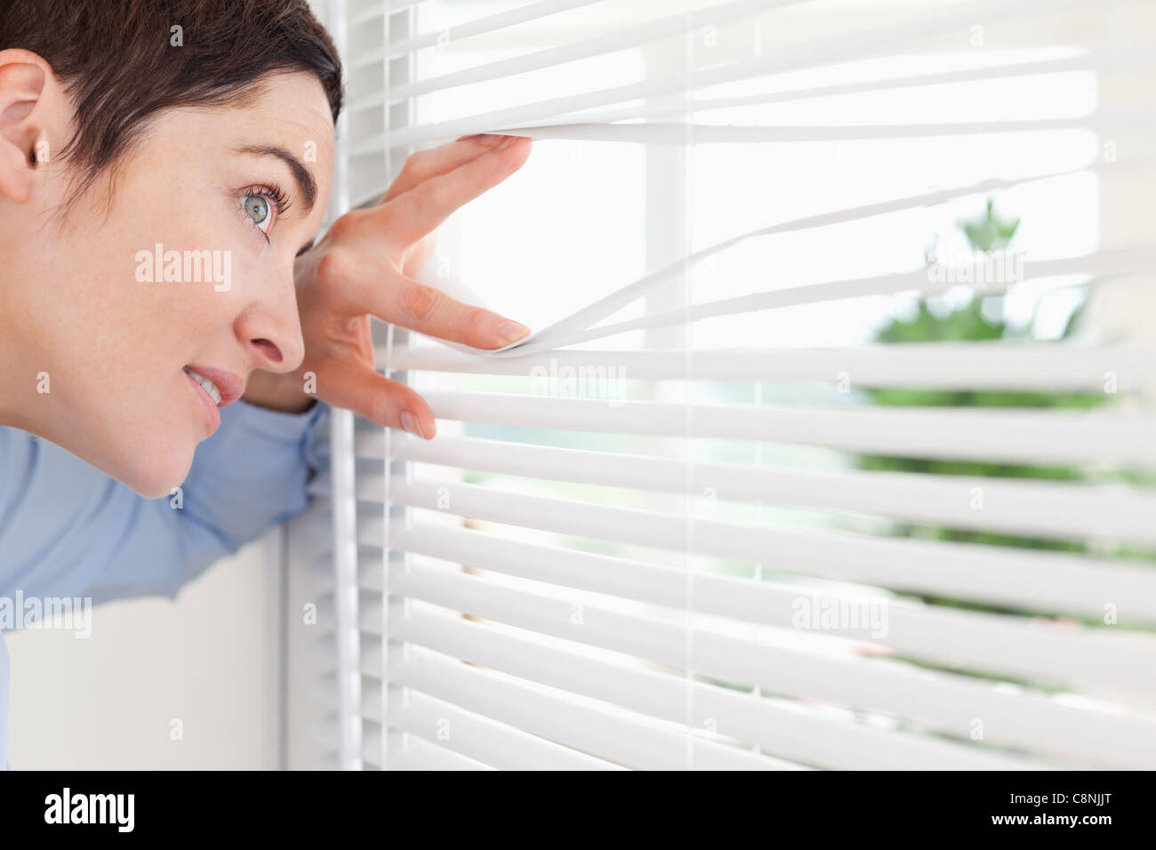 Charming woman peeking out a window Stock Photo - Alamy