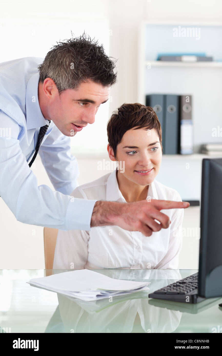Portrait of a man pointing at something on a screen to his secretary ...