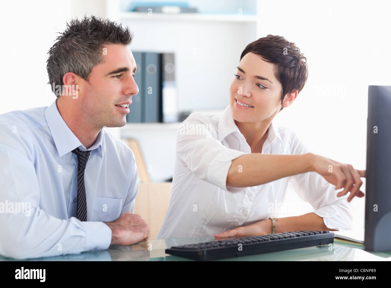 Office worker pointing a something on a screen to her colleague Stock ...