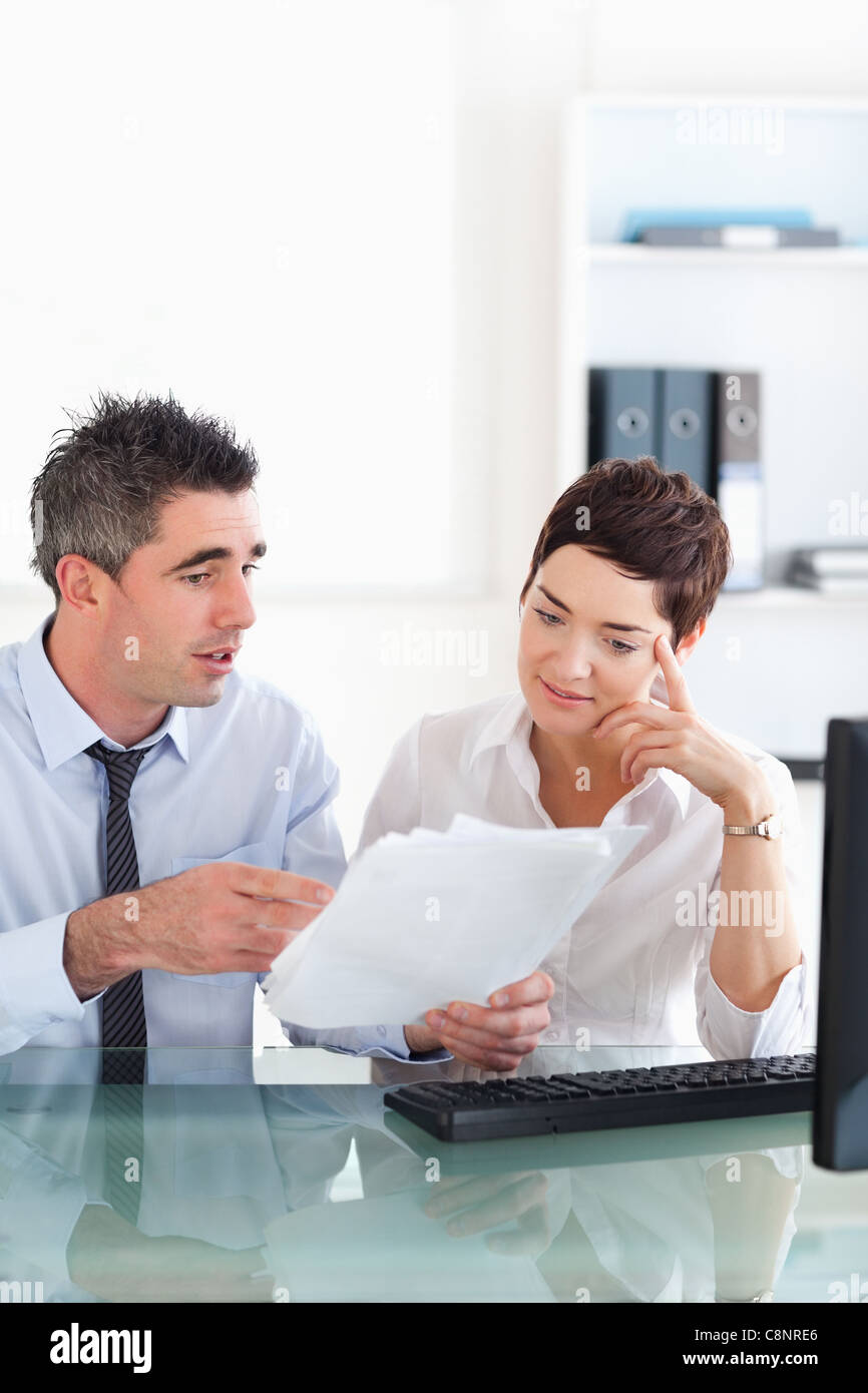 Manager pointing at something to his secretary on a blueprint document ...