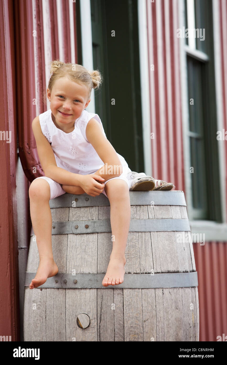 Smiling Caucasian girl sitting on barrel Stock Photo - Alamy