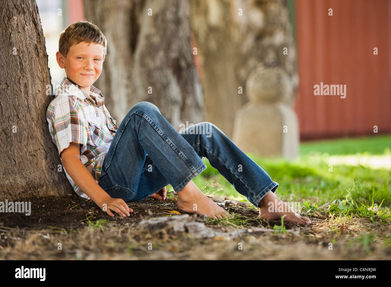 Boy leaning against tree trunk hi-res stock photography and images - Alamy