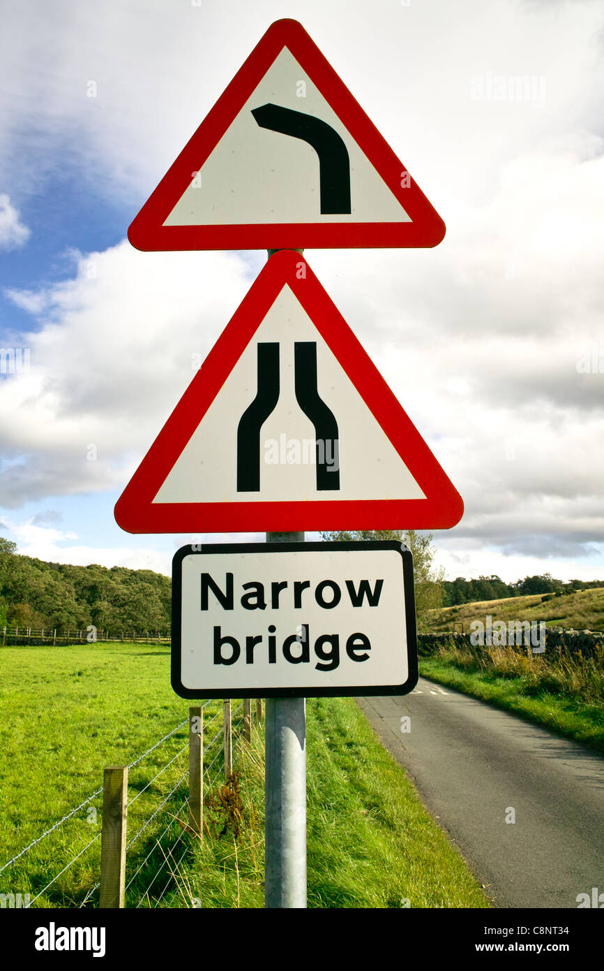 Close up of road sign indicating a narrow bridge and road bending to ...