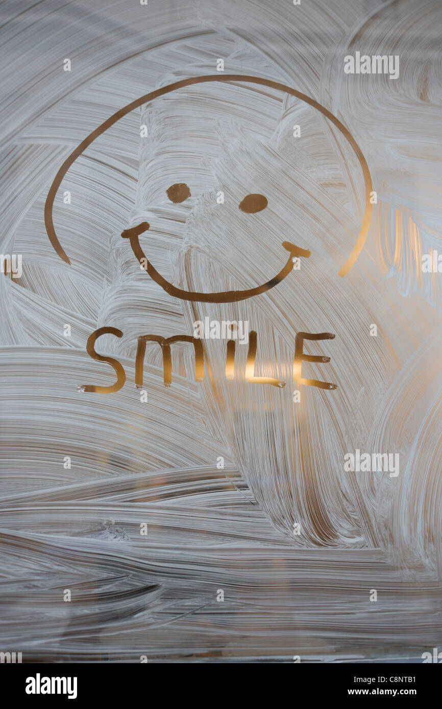 A happy, optimistic smiley hand-drawn on a whitewashed window of a soon ...