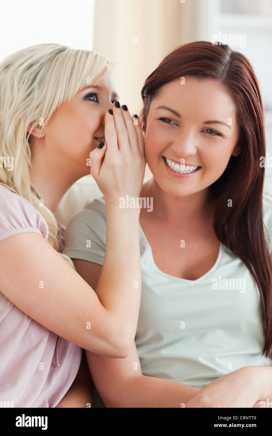 Smiling young woman telling her friend a secret Stock Photo - Alamy