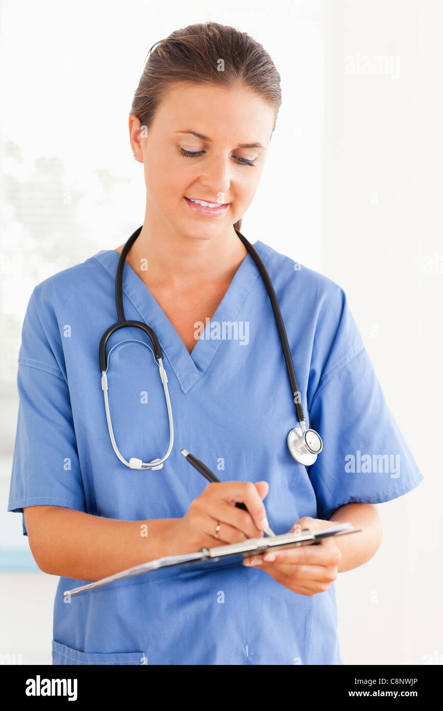 Nurse writing in a folder with a pen Stock Photo - Alamy