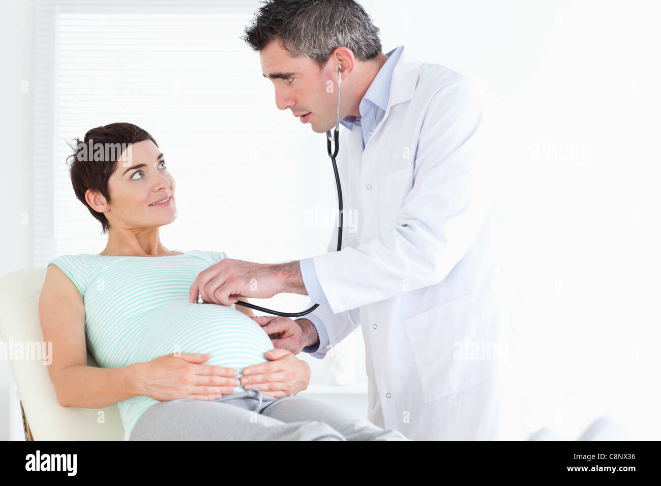 Doctor examining the woman's tummy with a stethoscope Stock Photo - Alamy