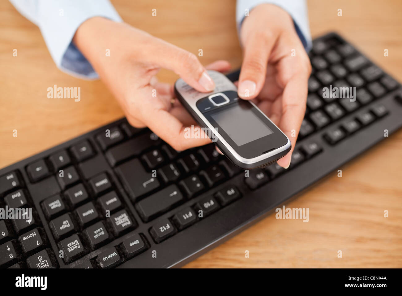 Woman holding mobile phone above keyboard Stock Photo - Alamy