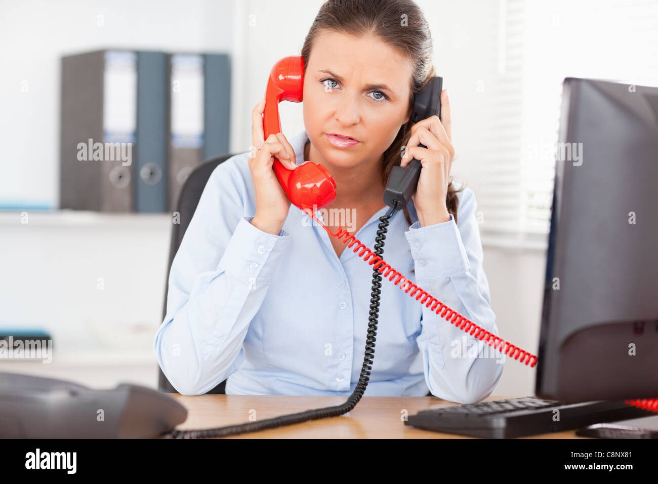 Secretary telephoning with two telephones Stock Photo - Alamy