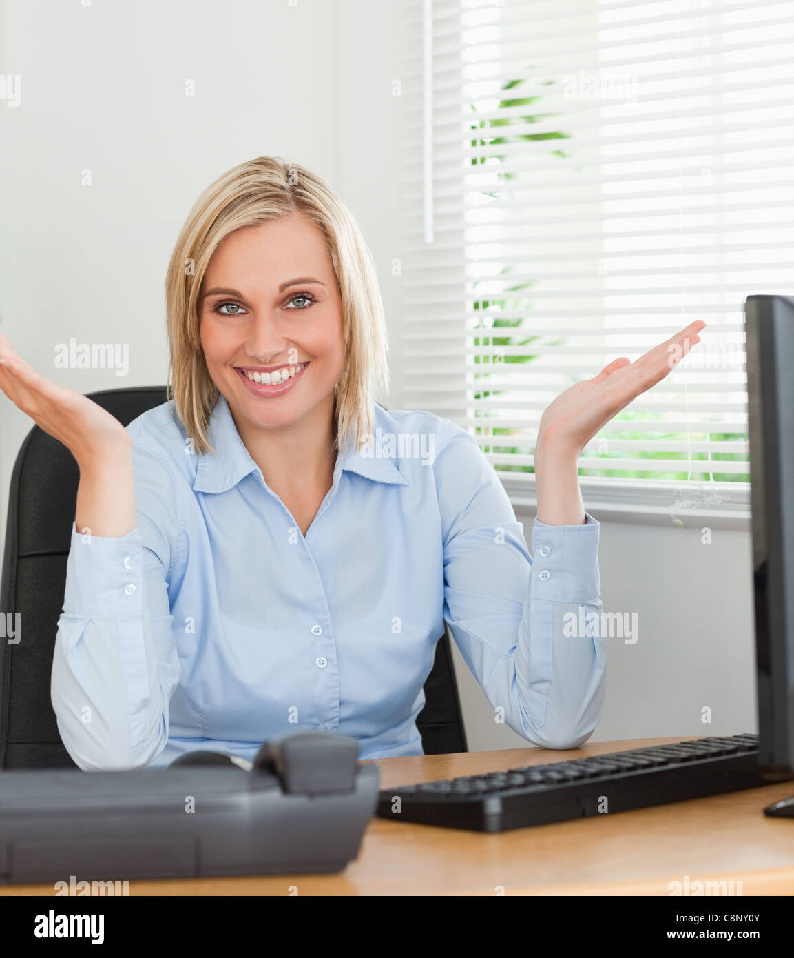 Smiling woman sitting behind desk not having a clue what to do next ...