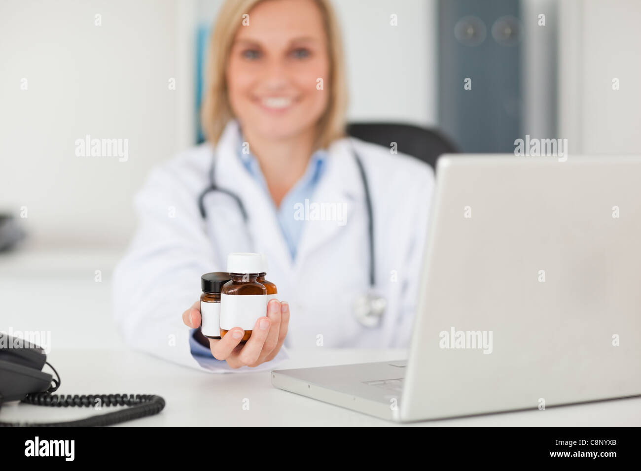 Smiling blonde doctor presenting medicine Stock Photo - Alamy