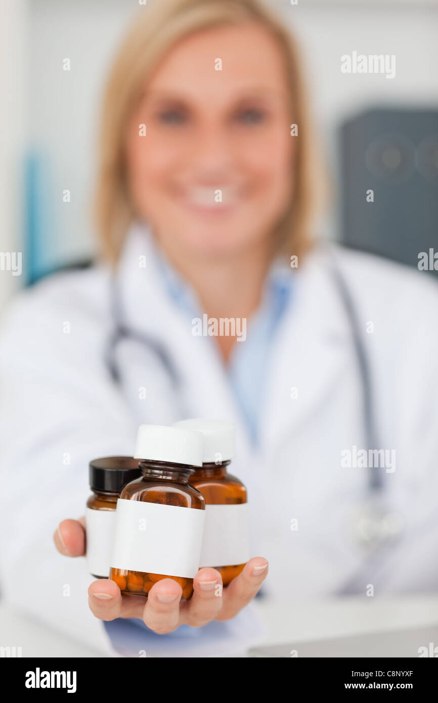 Smiling blonde doctor holding medicine Stock Photo - Alamy