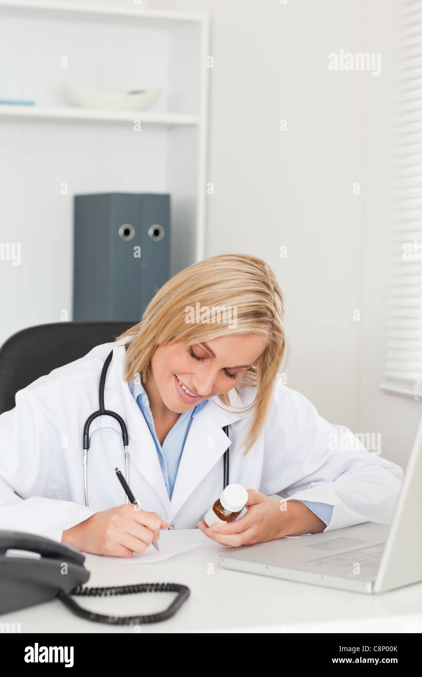 Doctor writing something down while holding medicine Stock Photo - Alamy