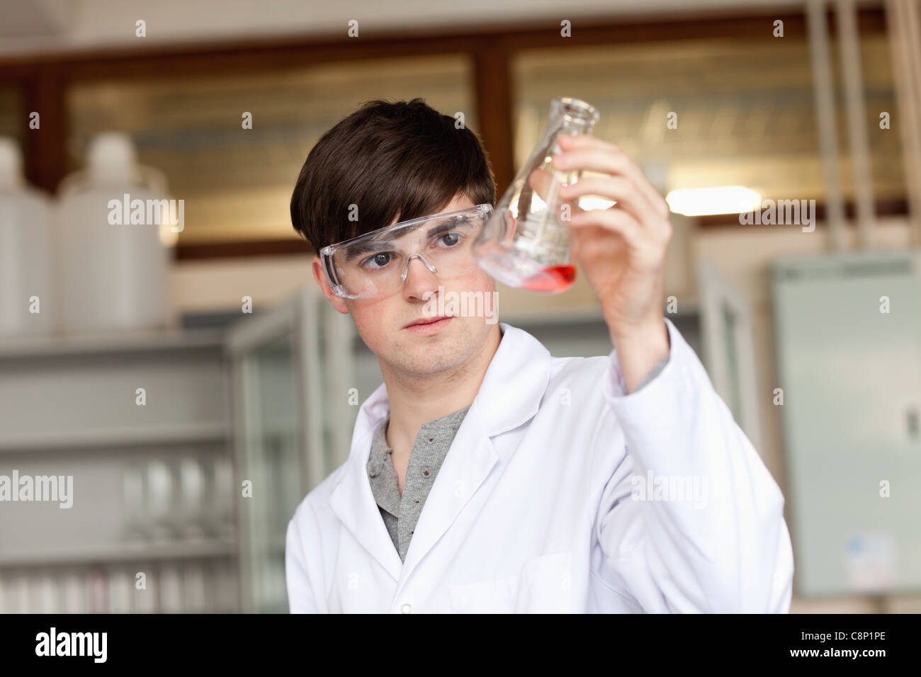 Scientist looking at a liquid in an Erlenmeyer flask Stock Photo - Alamy