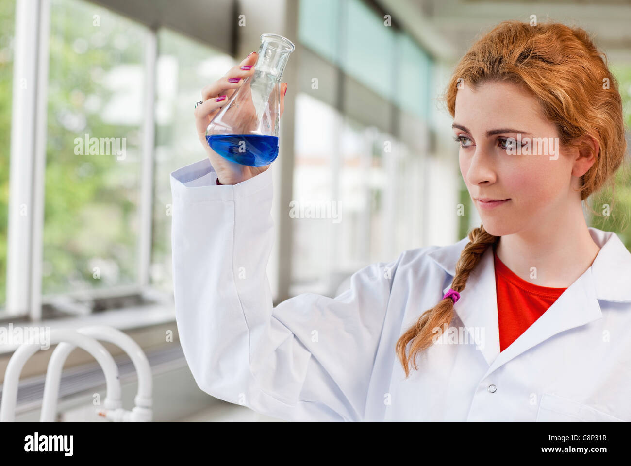 Chemist looking at a blue liquid Stock Photo - Alamy