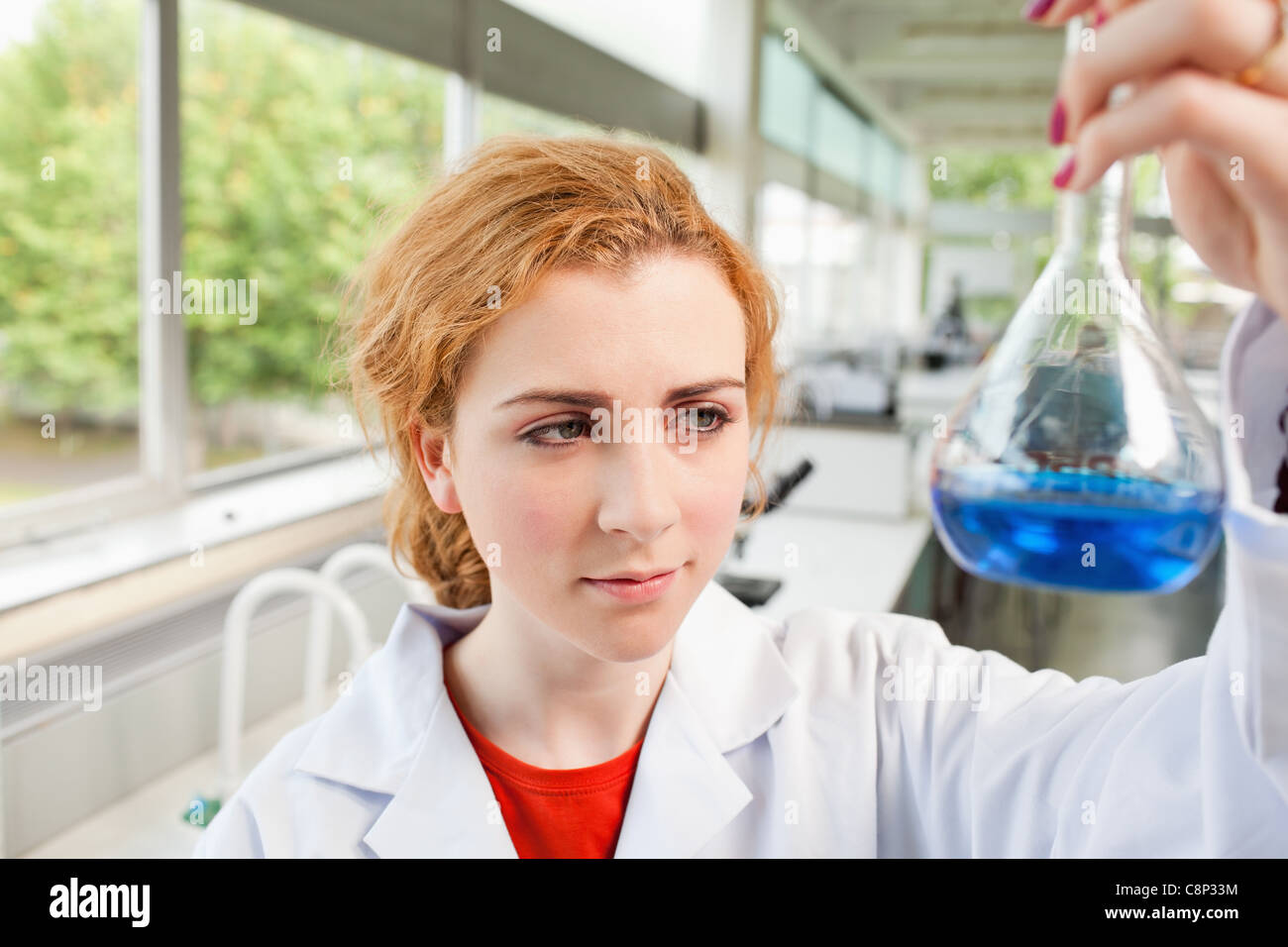 Cute science student holding a blue liquid Stock Photo - Alamy