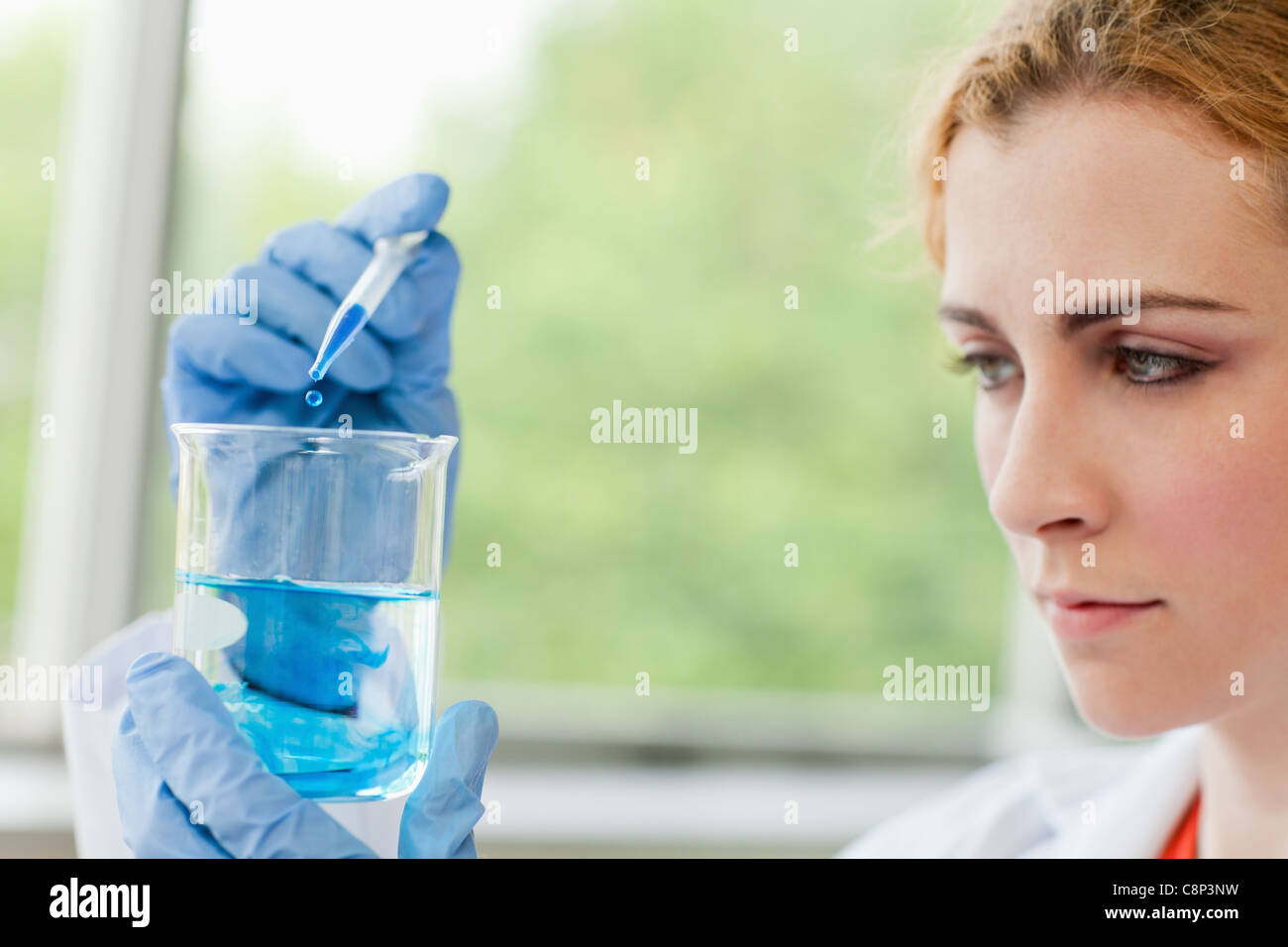 Cute scientist dropping liquid in a beaker Stock Photo - Alamy
