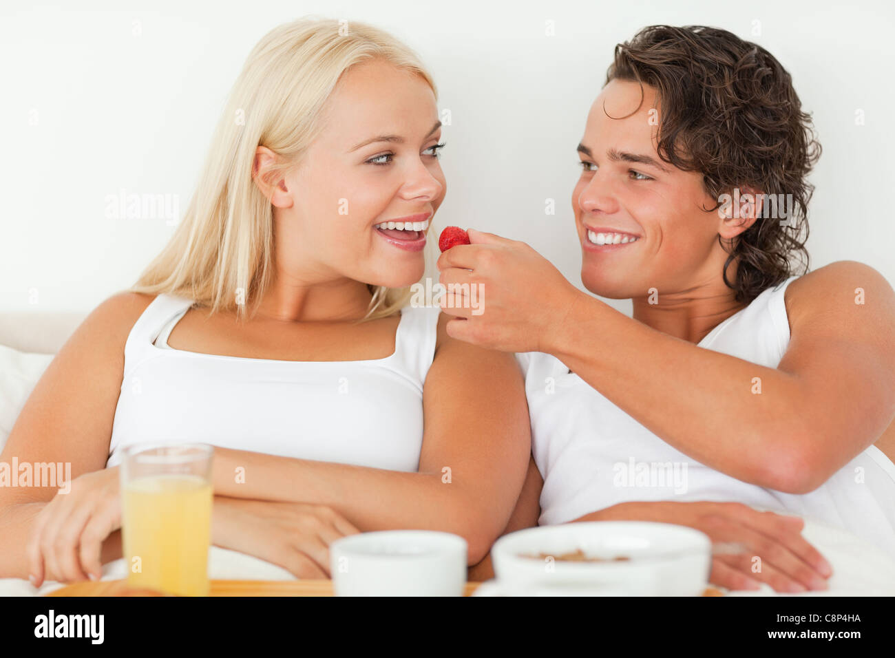 Cute man giving a strawberry to his girlfriend Stock Photo - Alamy