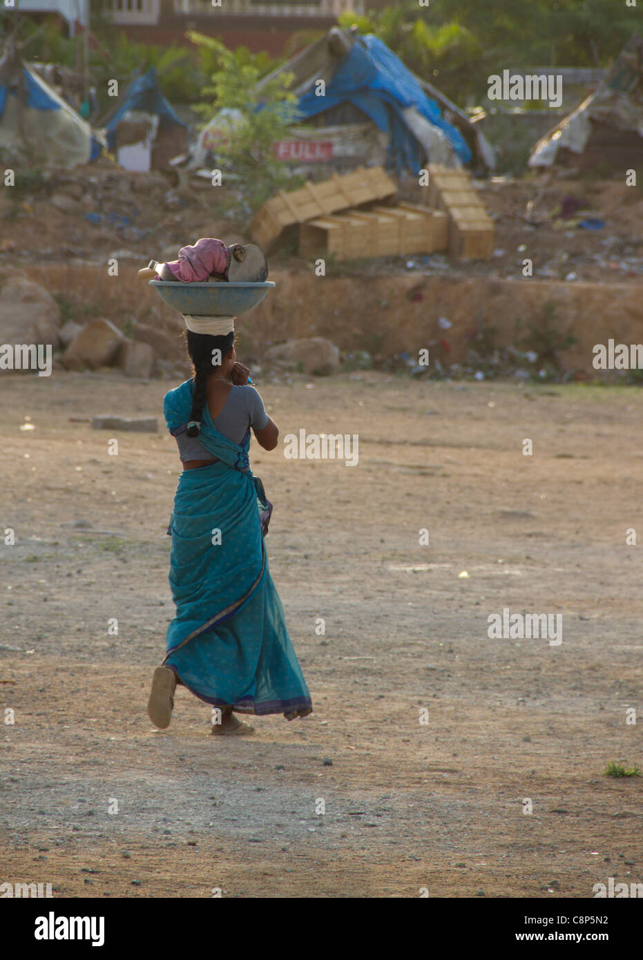 A young woman walks across the dirt field on her way to the slum ...