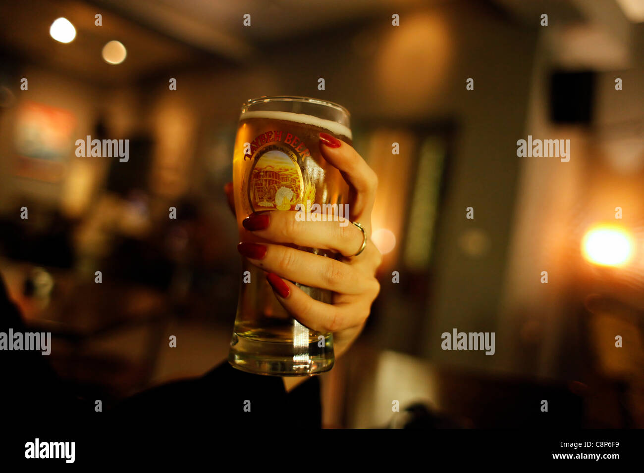 A woman holds a glass filled with the local Palestinian Taybeh beer in ...